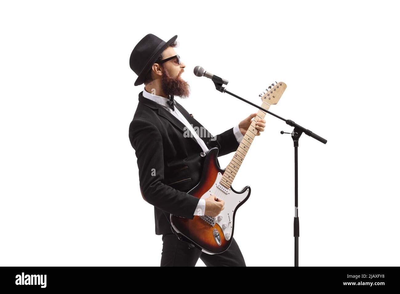 Profile shot of a male artist playing a guitar and singing on a mic ...