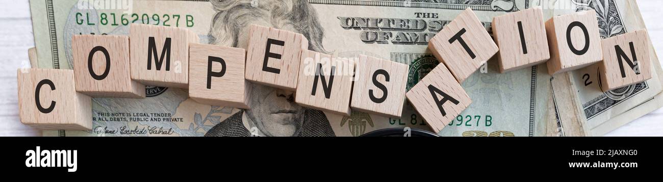 Compensation word written on wood block with American Dollar-bills ...