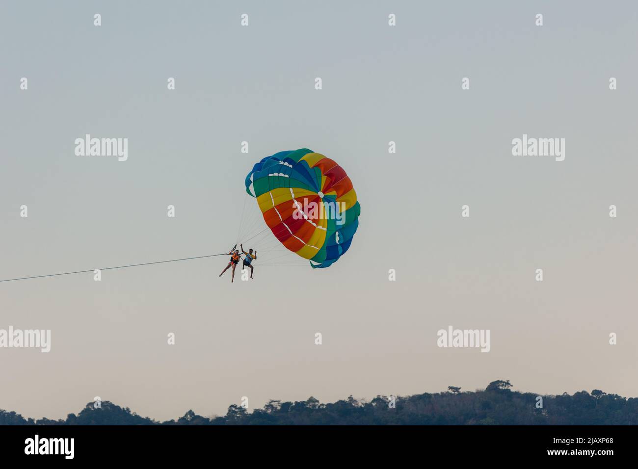 Couple paragliding in a coloured parachute Stock Photo - Alamy