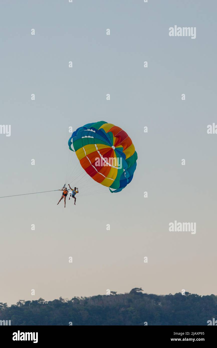 Couple paragliding in a coloured parachute Stock Photo - Alamy