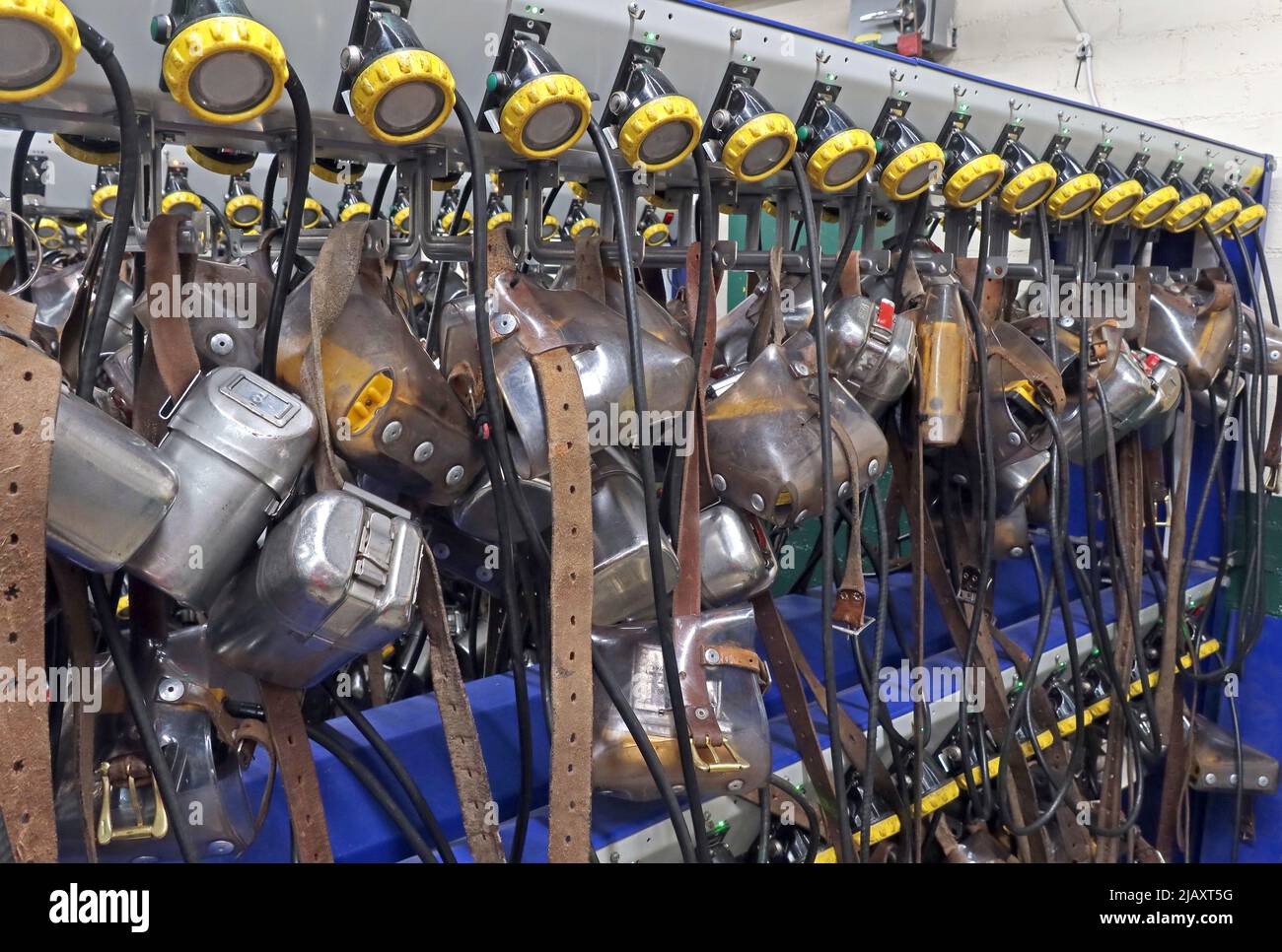 Multiple coal miners lamps on belts charging batteries, lamp room in a ...