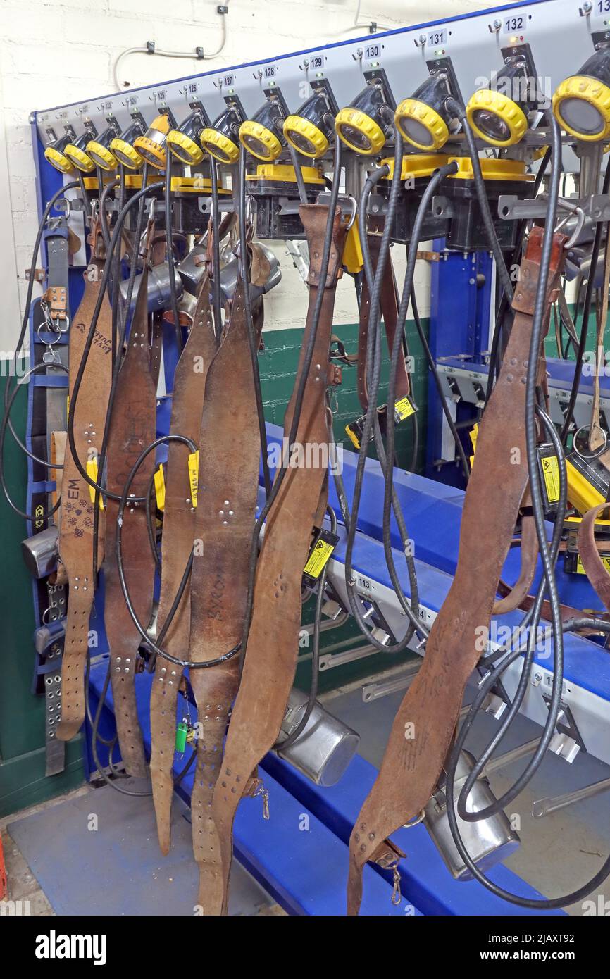 Multiple coal miners lamps on belts charging batteries, lamp room in a ...