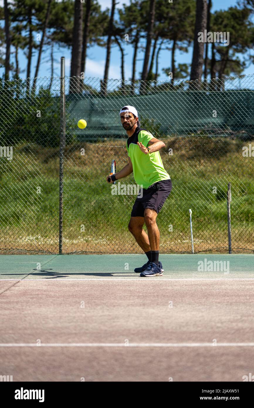 Tennis player hitting forehand at ball with racket on court Stock Photo ...