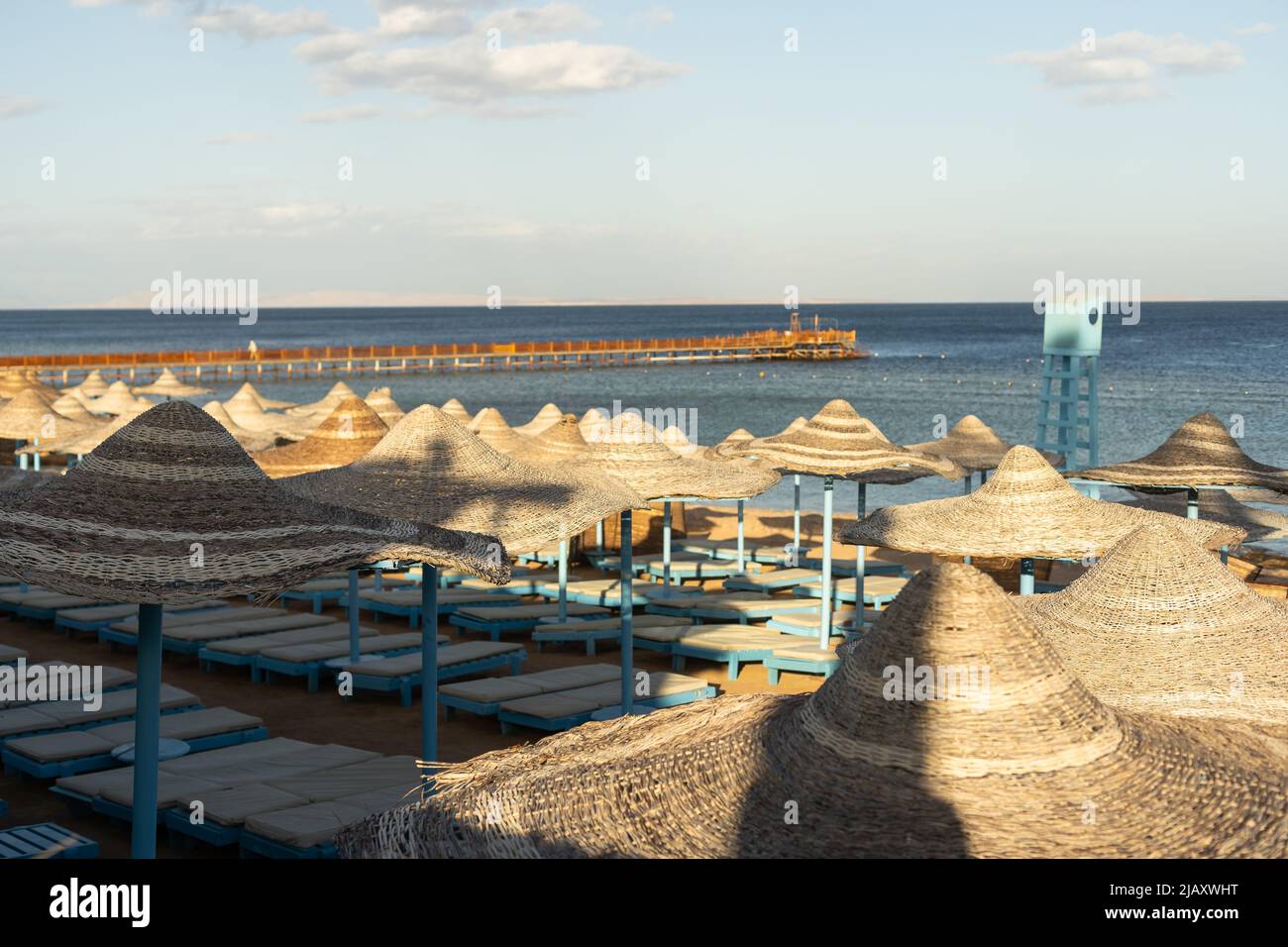 Mediterranean coast with sunbeds and straw sun umbrellas on the sandy ...