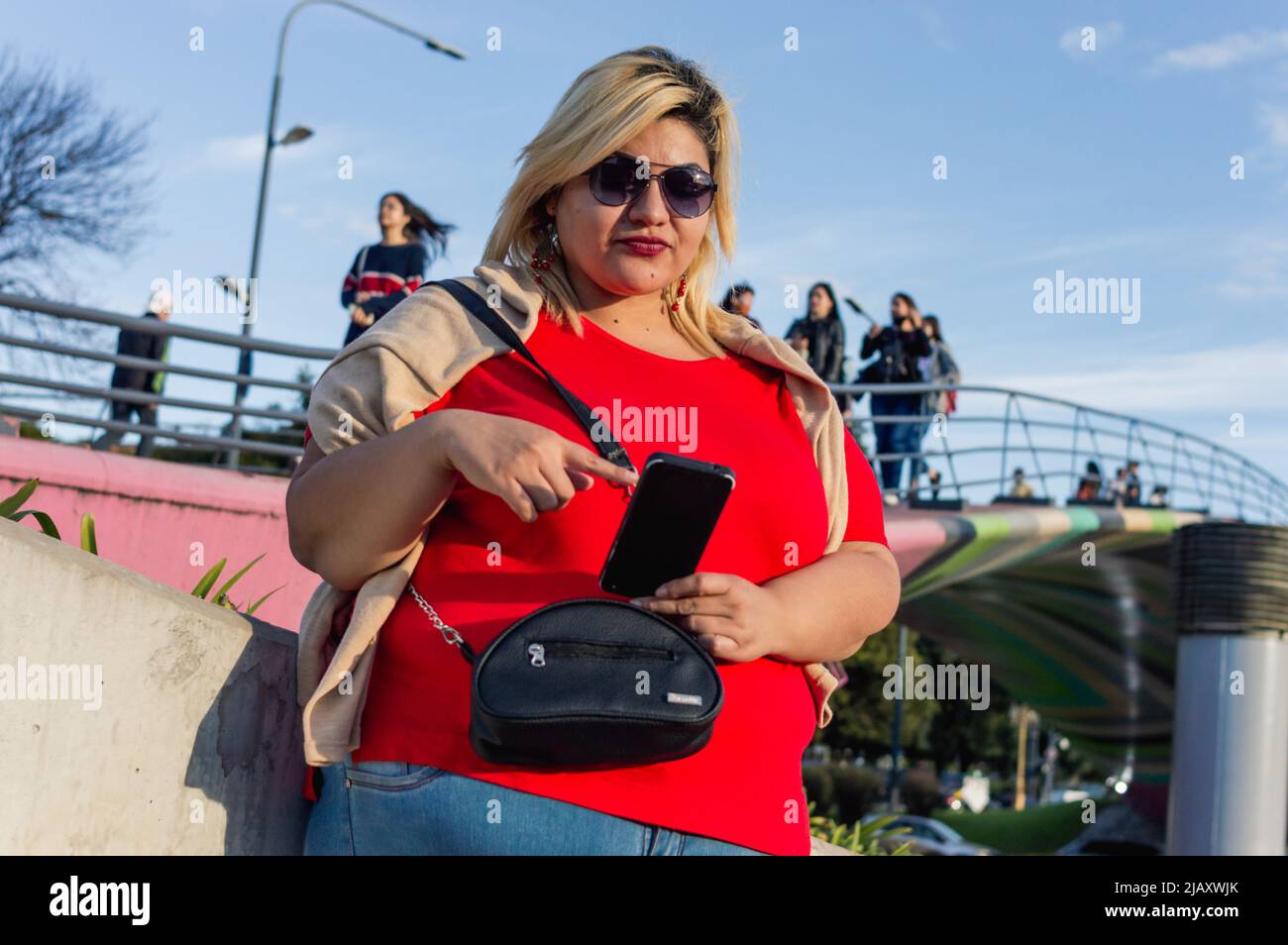 young latin plus size woman outdoors texting on her phone, leaning ...