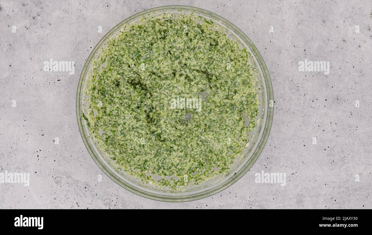 Mascarpone and spinach mix close up in a glass bowl on light grey ...