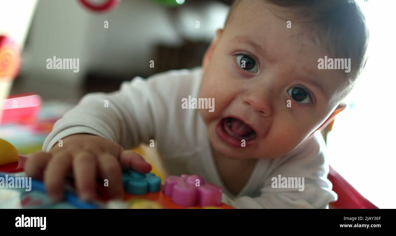 Cute baby portrait on floor at nursery room. Infant child face touching ...