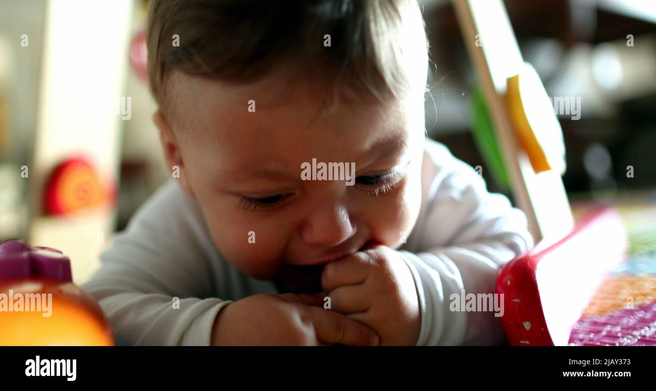 Cute baby portrait on floor at nursery room. Infant child face touching ...