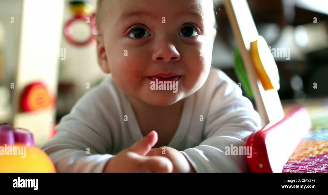 Cute baby portrait on floor at nursery room. Infant child face touching ...