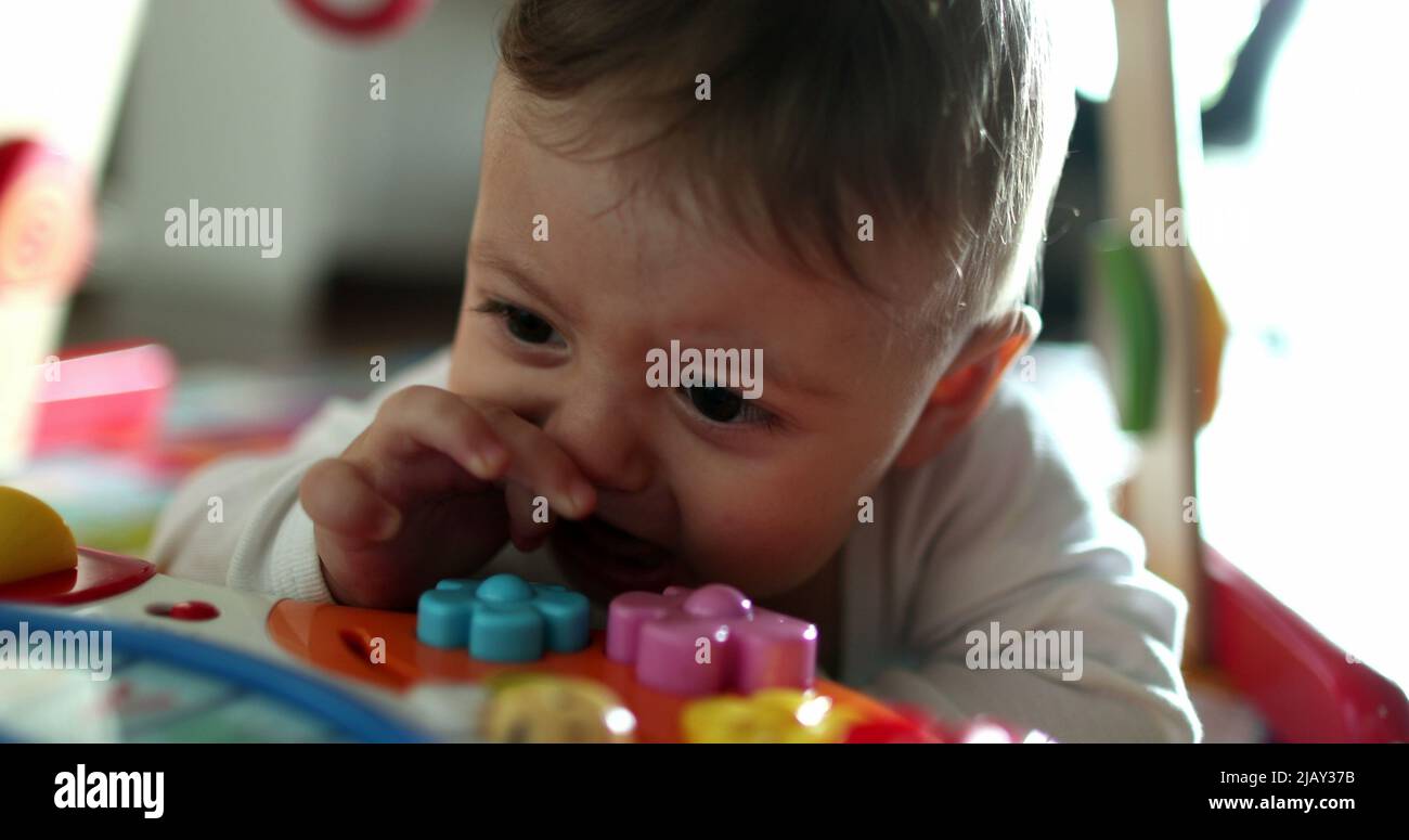 Cute baby portrait on floor at nursery room. Infant child face touching ...