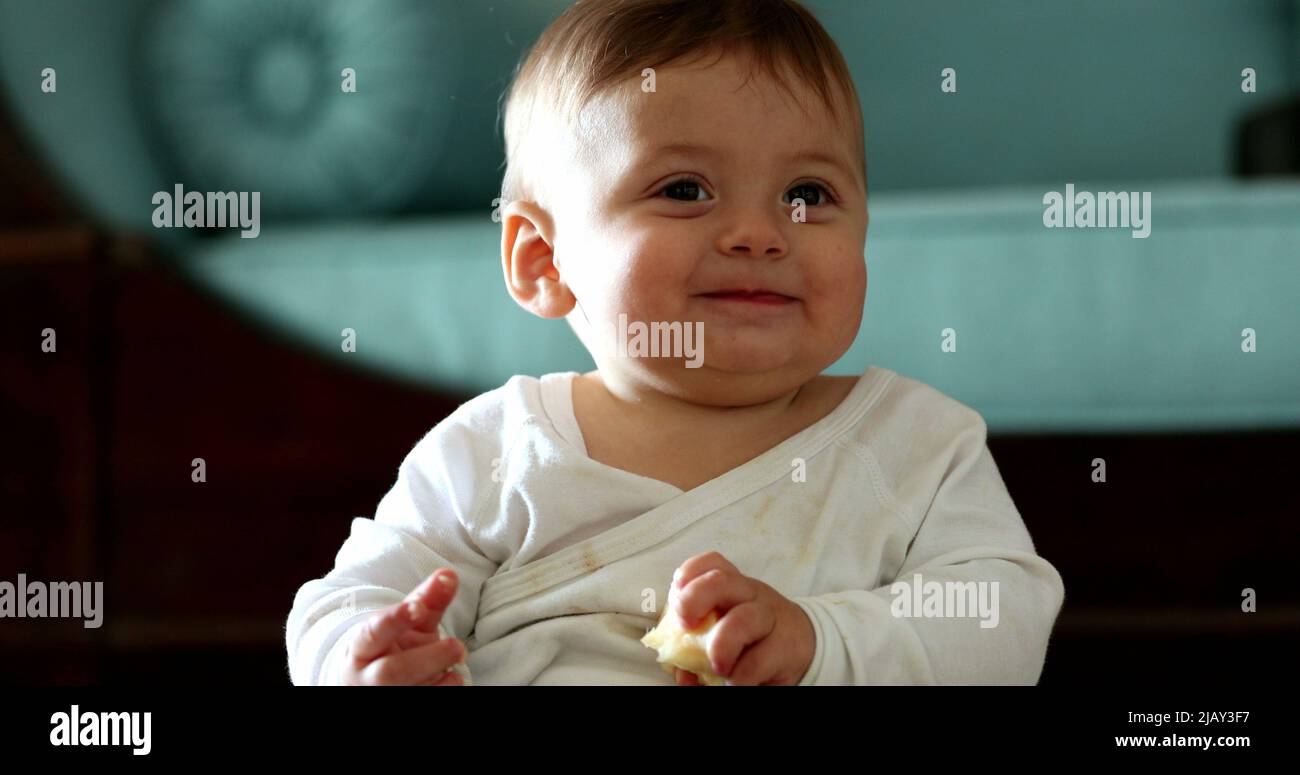 Cute happy baby eating apple fruit snack, infant smiling and laughing ...