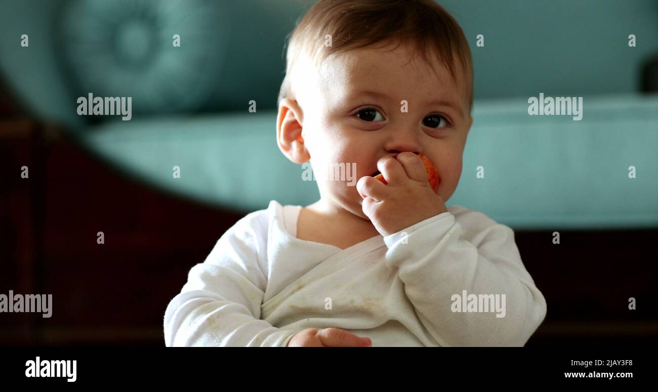 Cute happy baby eating apple fruit snack, infant smiling and laughing ...