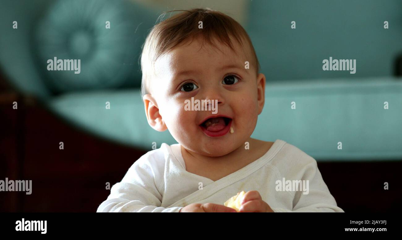 Cute happy baby eating apple fruit snack, infant smiling and laughing ...