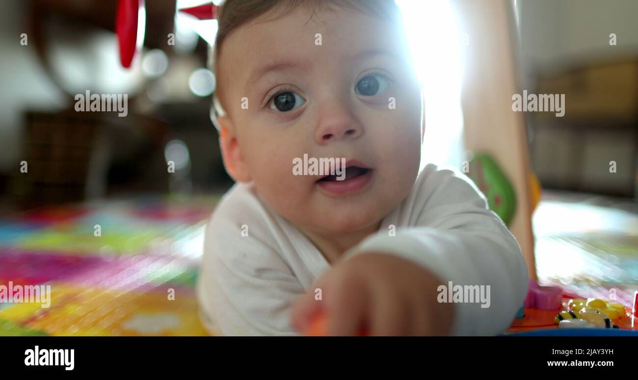 Infant baby playing with toy indoors. Portrait face smiling feeling joy ...