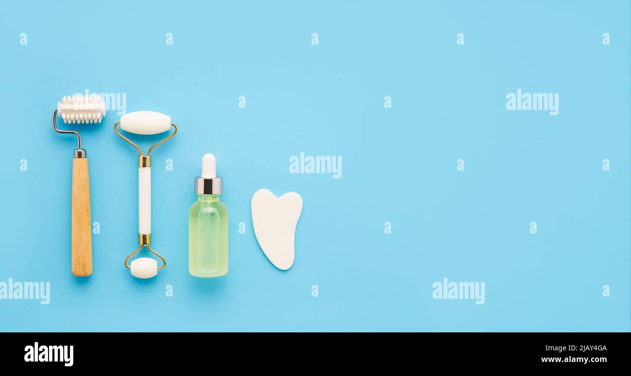 Set of massage roller and gua sha for face on blue background. Self ...