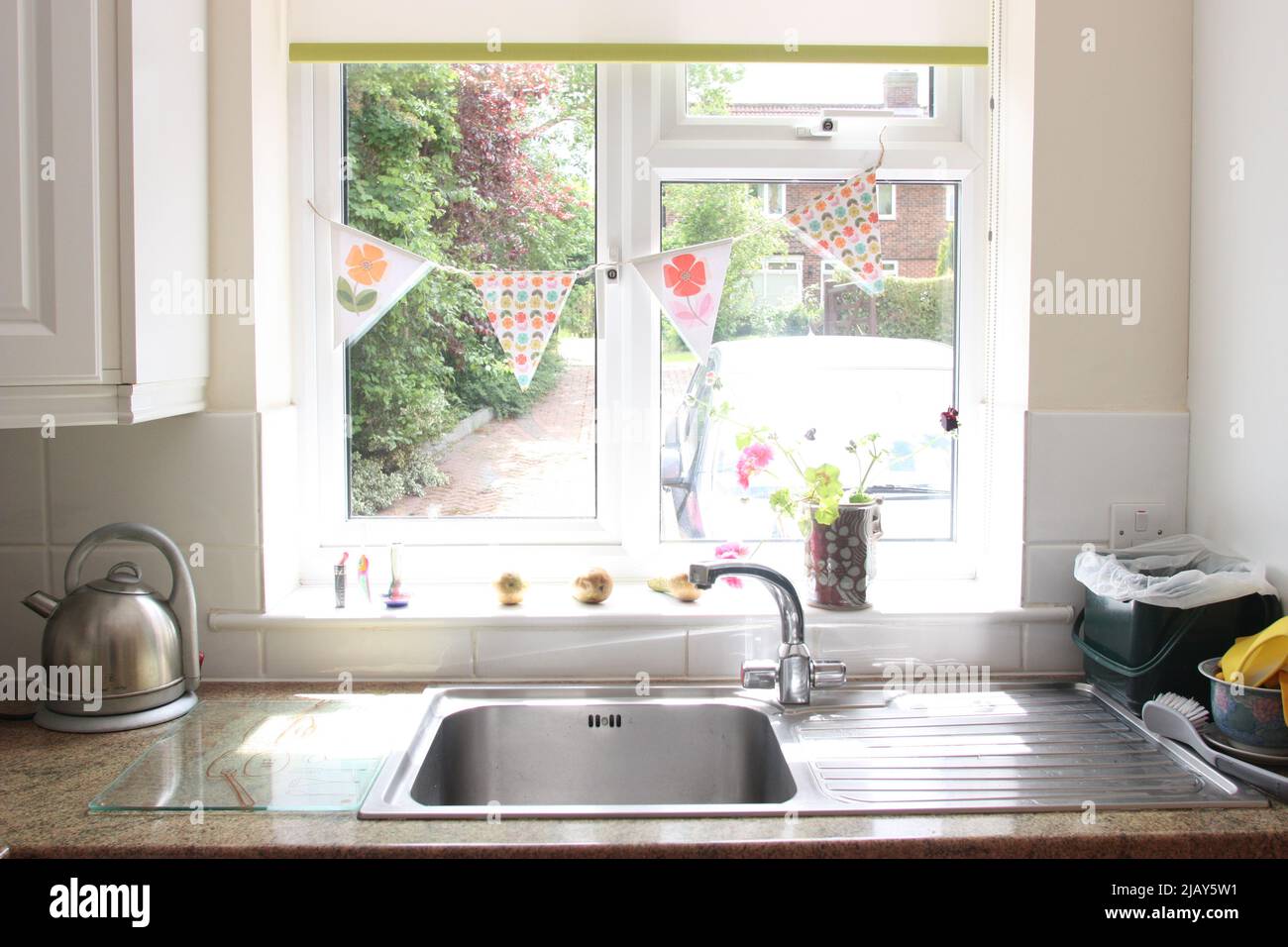 Kitchen sink, draining board, kettle and window looking out onto paved ...