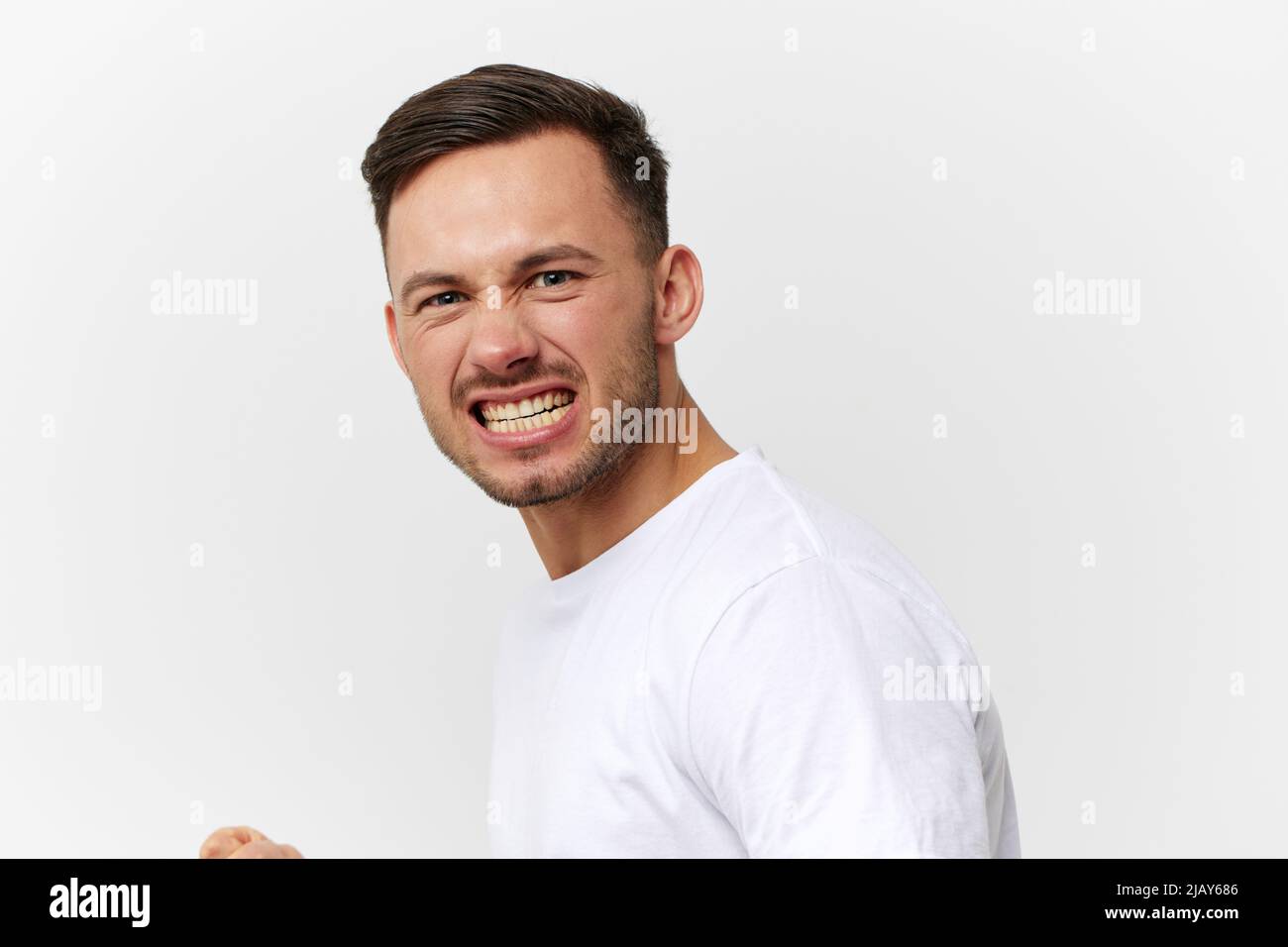 Aggressive evil tanned handsome man in basic t-shirt scream at camera ...