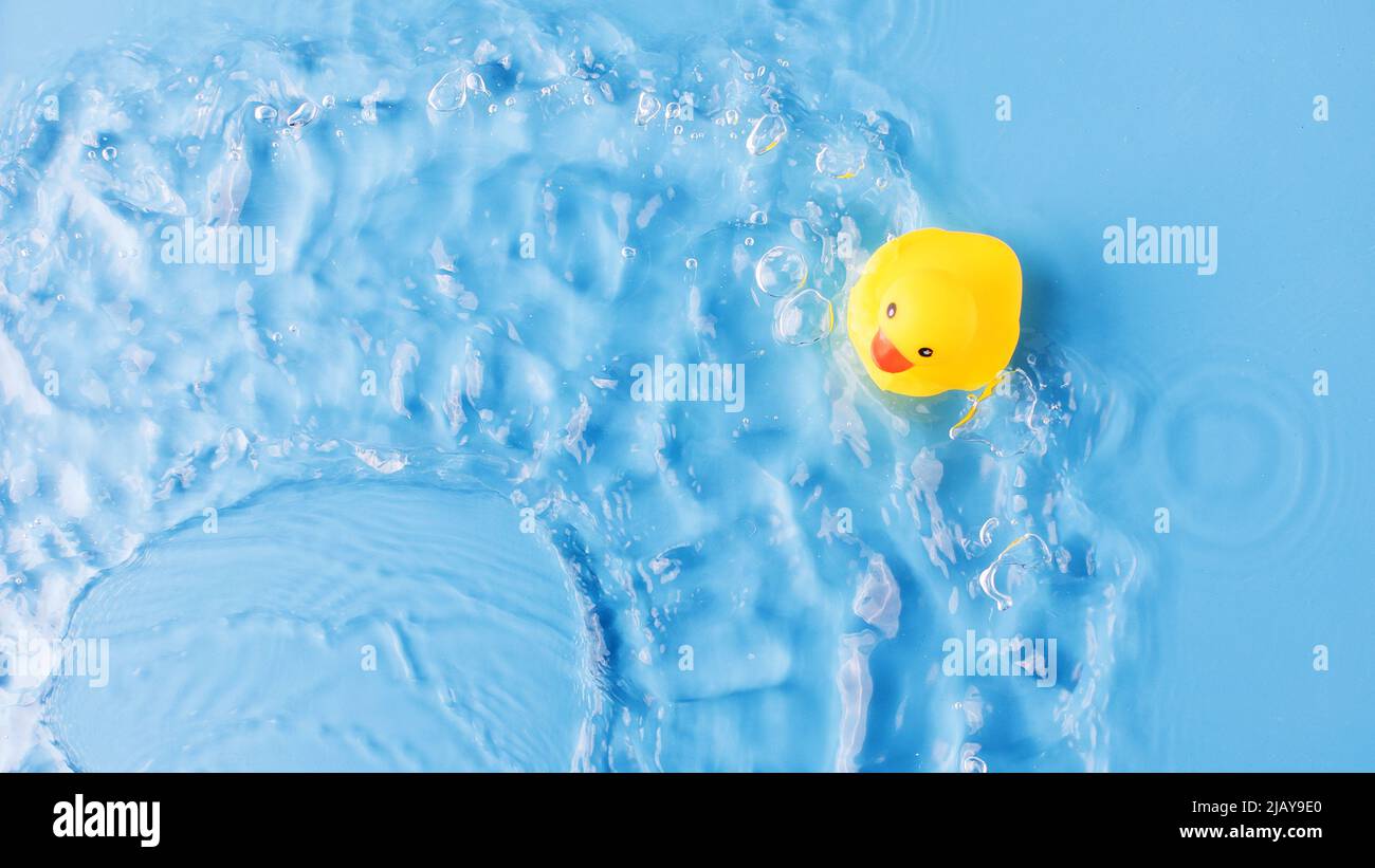 Funny rubber duck on splashing water on light blue background view from ...