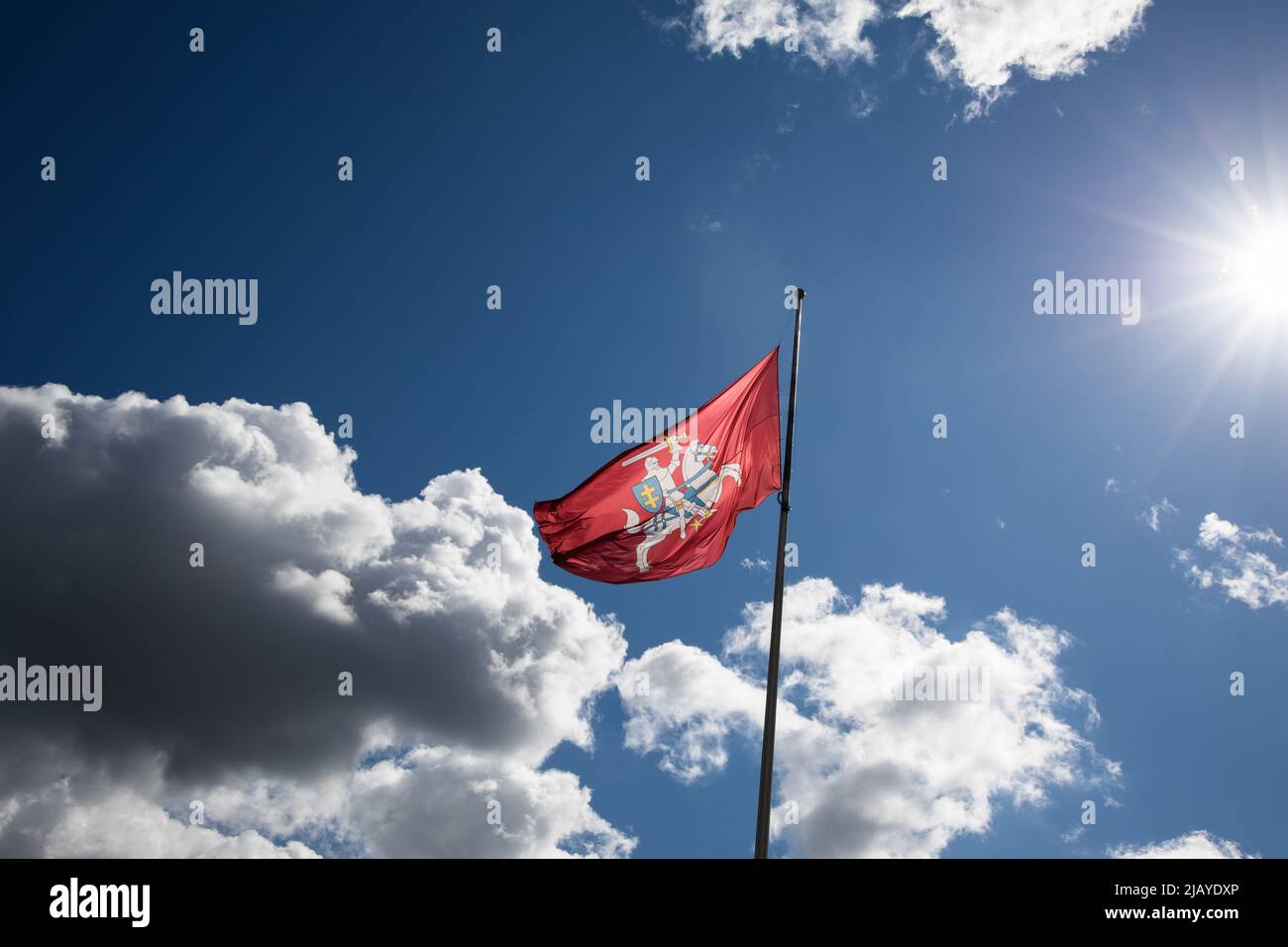 Waving flag with the coat of arms of Lithuania, against blue sky with ...