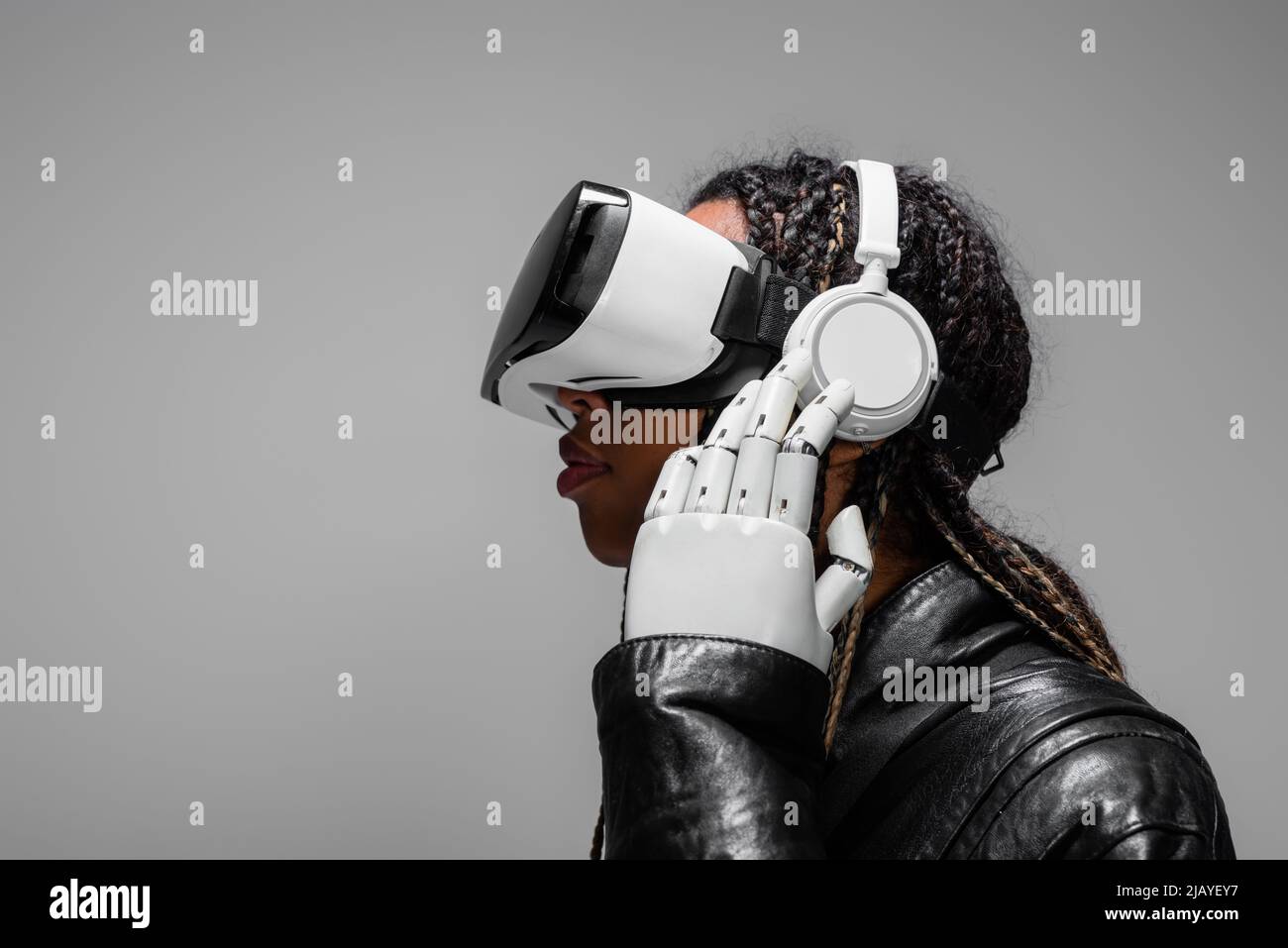 Side view of african american woman with robotic hand and vr headset ...