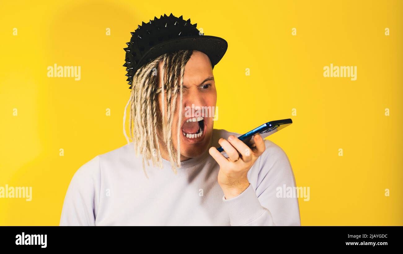 Young aggressive man shouts into mobile phone. Angry excited guy with ...