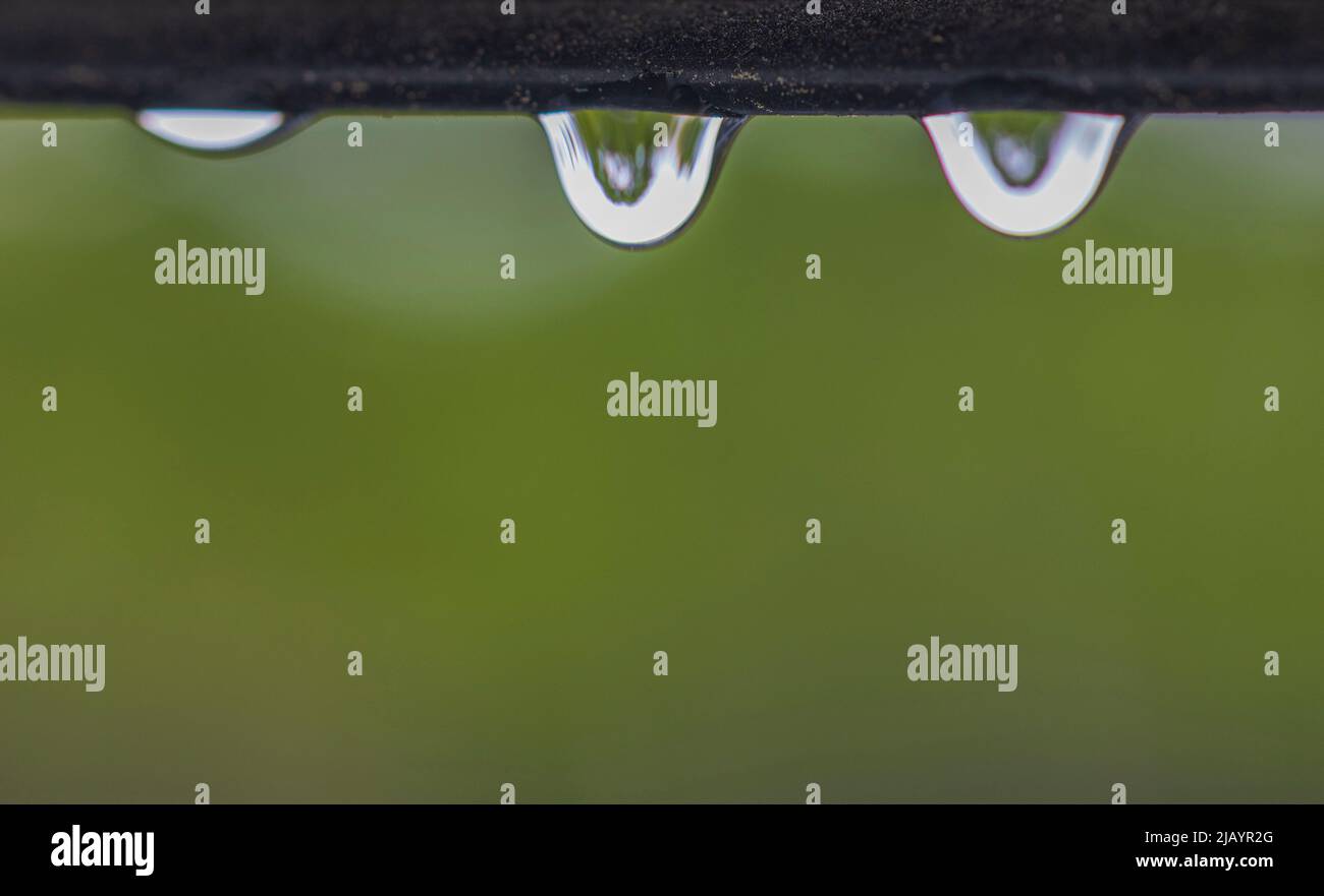 Close up macro view of falling raindrops from window frame of skylight ...