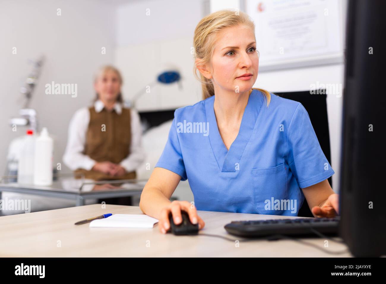 Female dermatologist recording patient examination results on computer ...