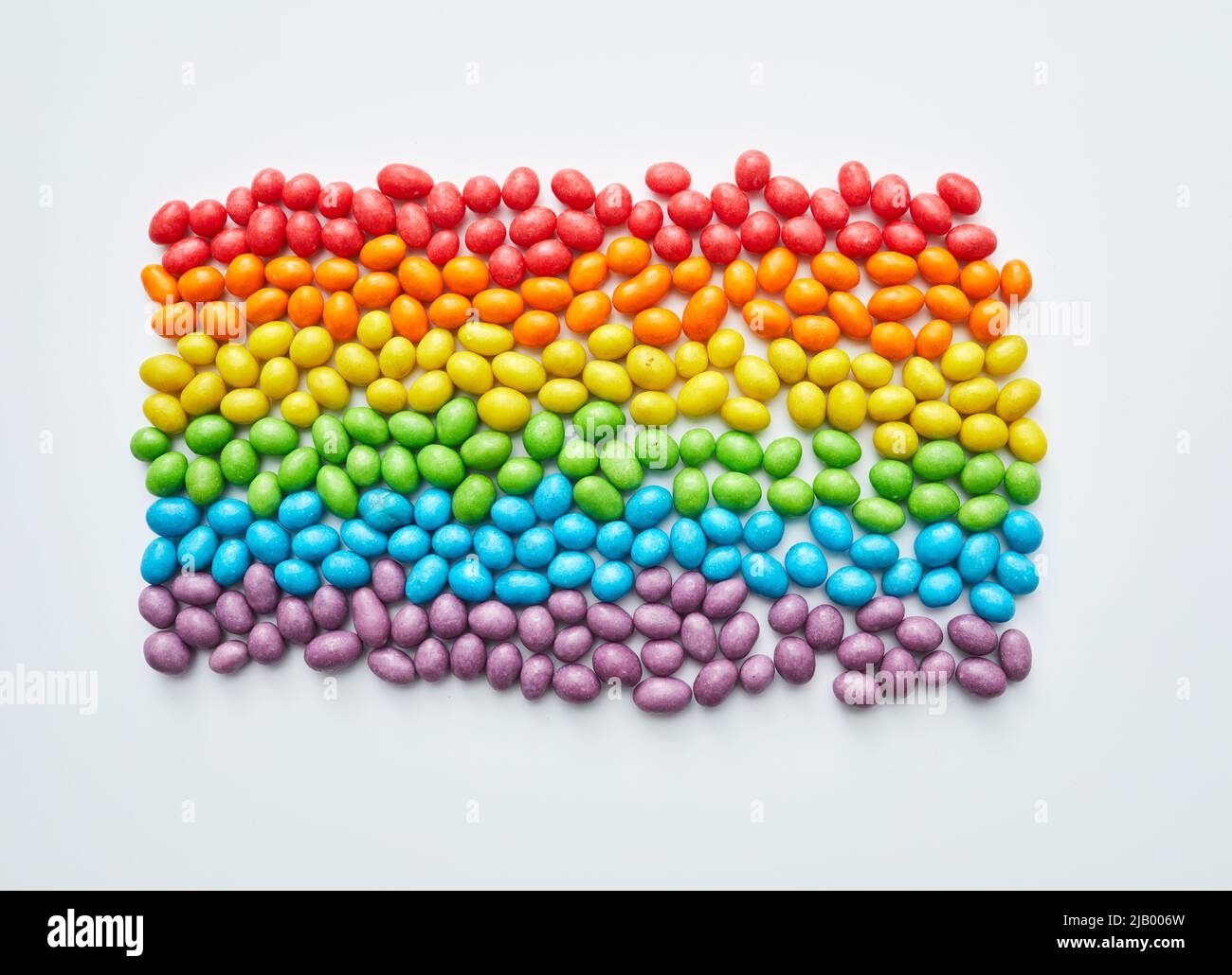 Multi-colored candies laid out in shape of equality flag on white ...