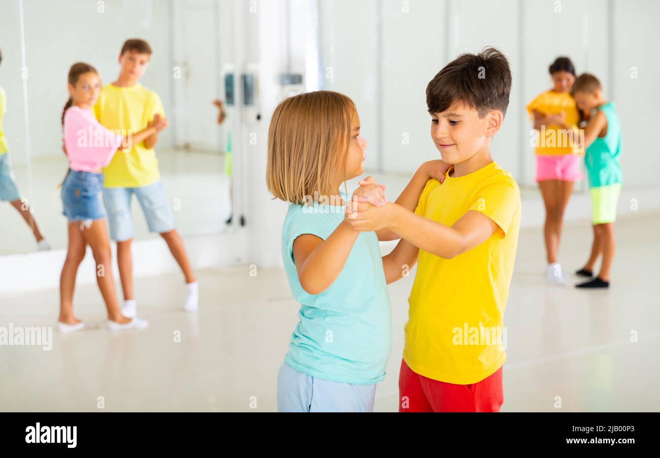 Tween boy and girl practicing slow pair dancing during group class ...