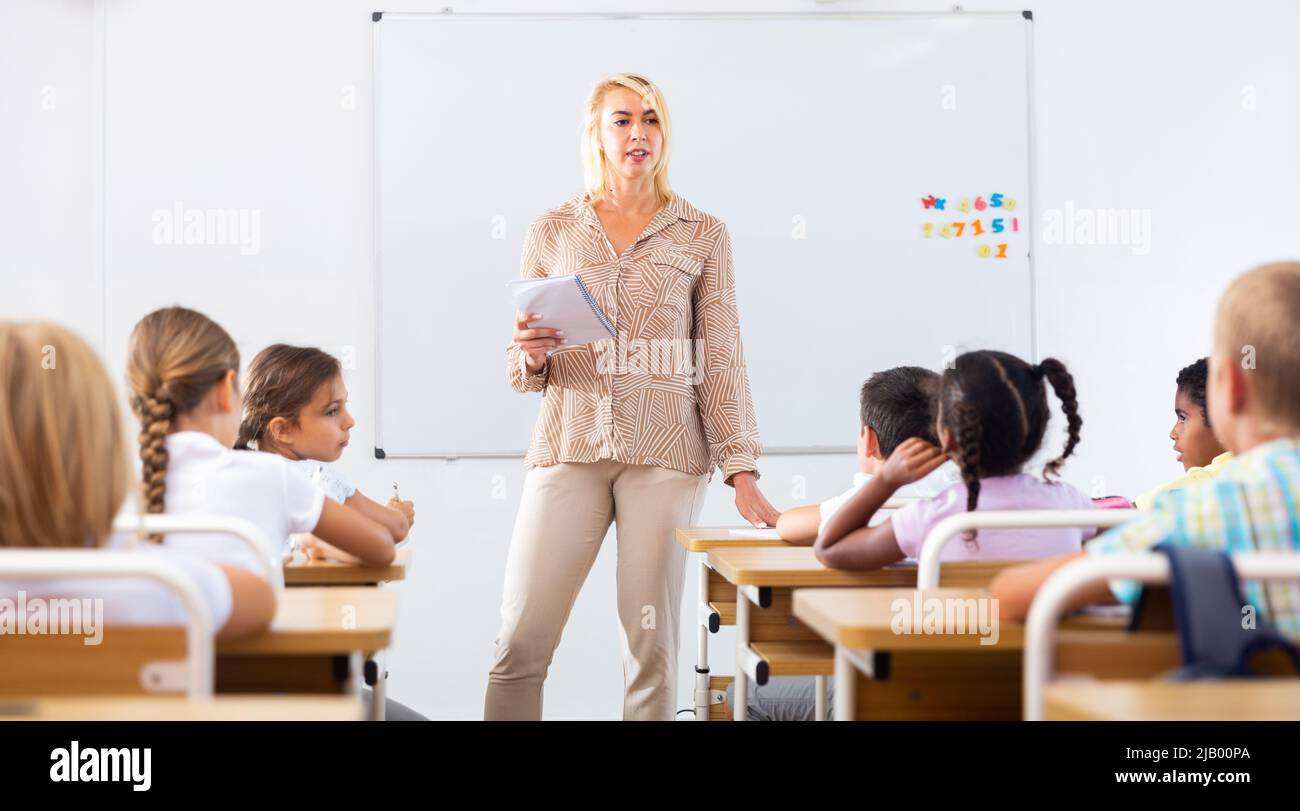 Woman teacher is giving interesting lecture for primary school students ...