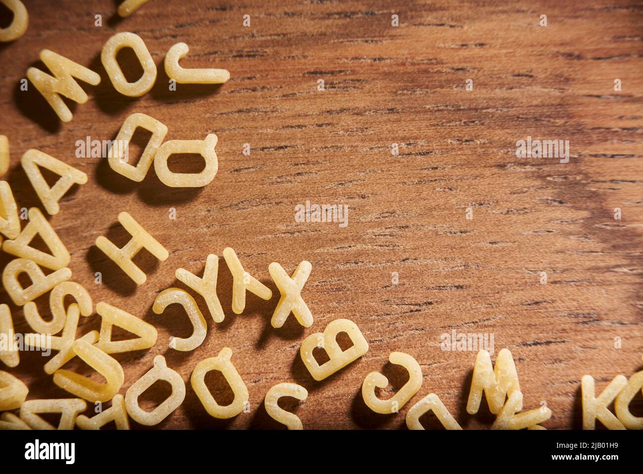 Uncooked alphabet soup pasta letters on a wooden background leaving ...
