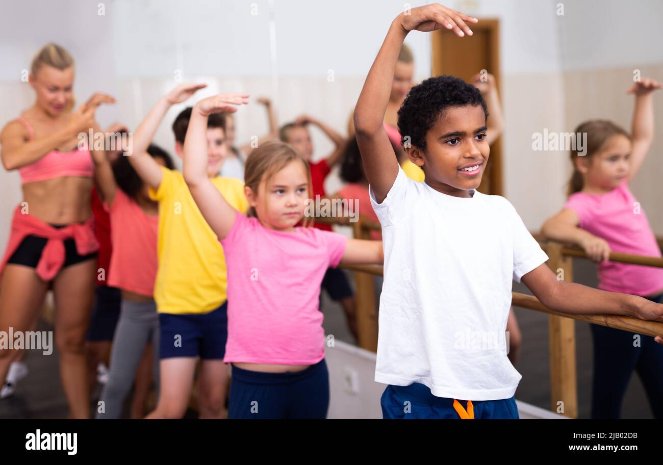 African boy practicing near ballet barre during group dance class Stock ...