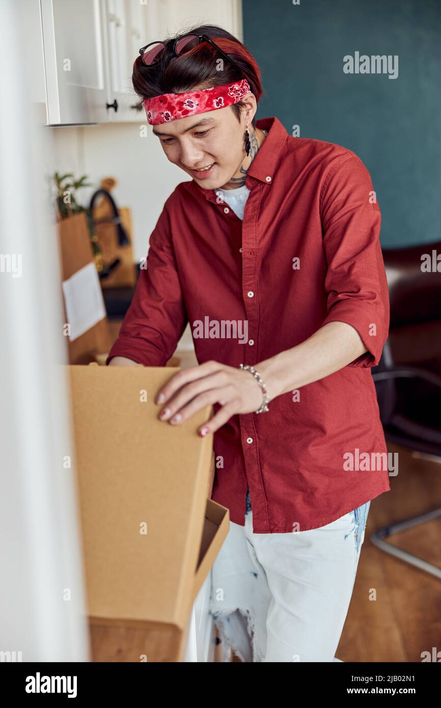 Happy Asian guy opening a paper box in the kitchen Stock Photo - Alamy