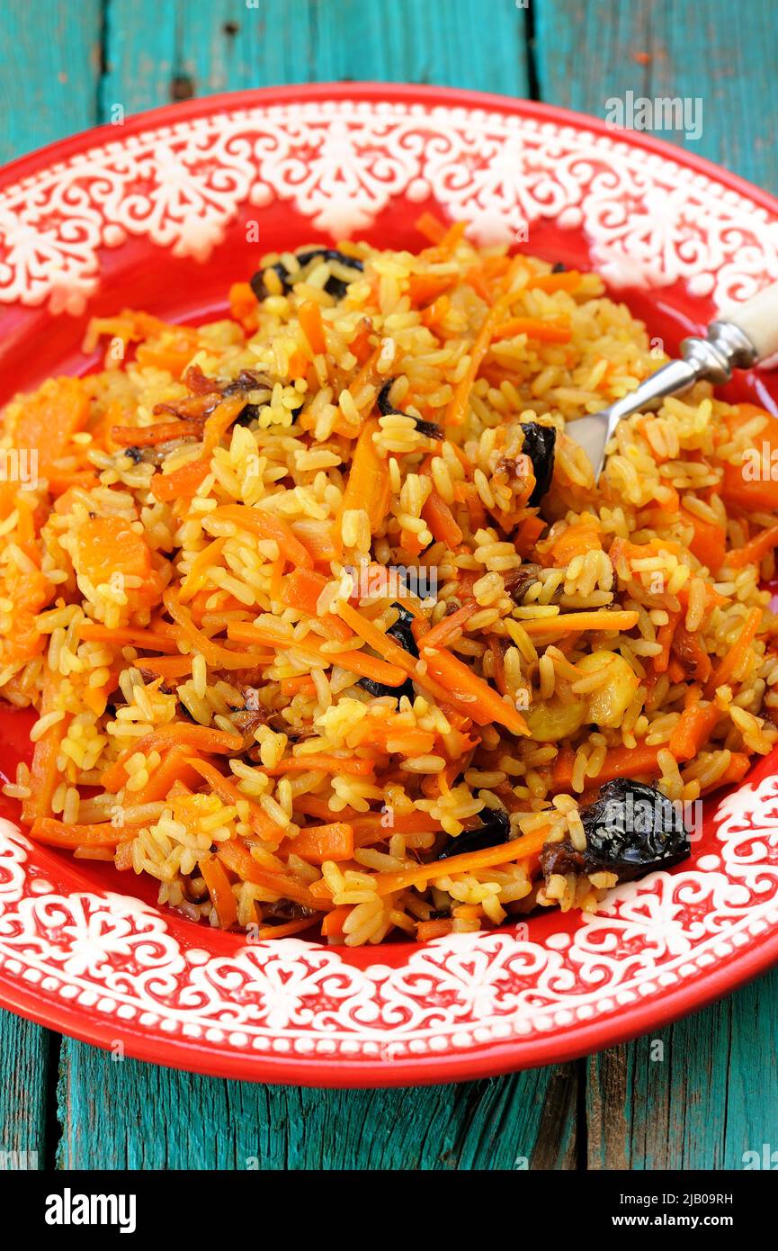 Homemade vegan pumpkin pilaf in red plate with white fork on turquoise ...