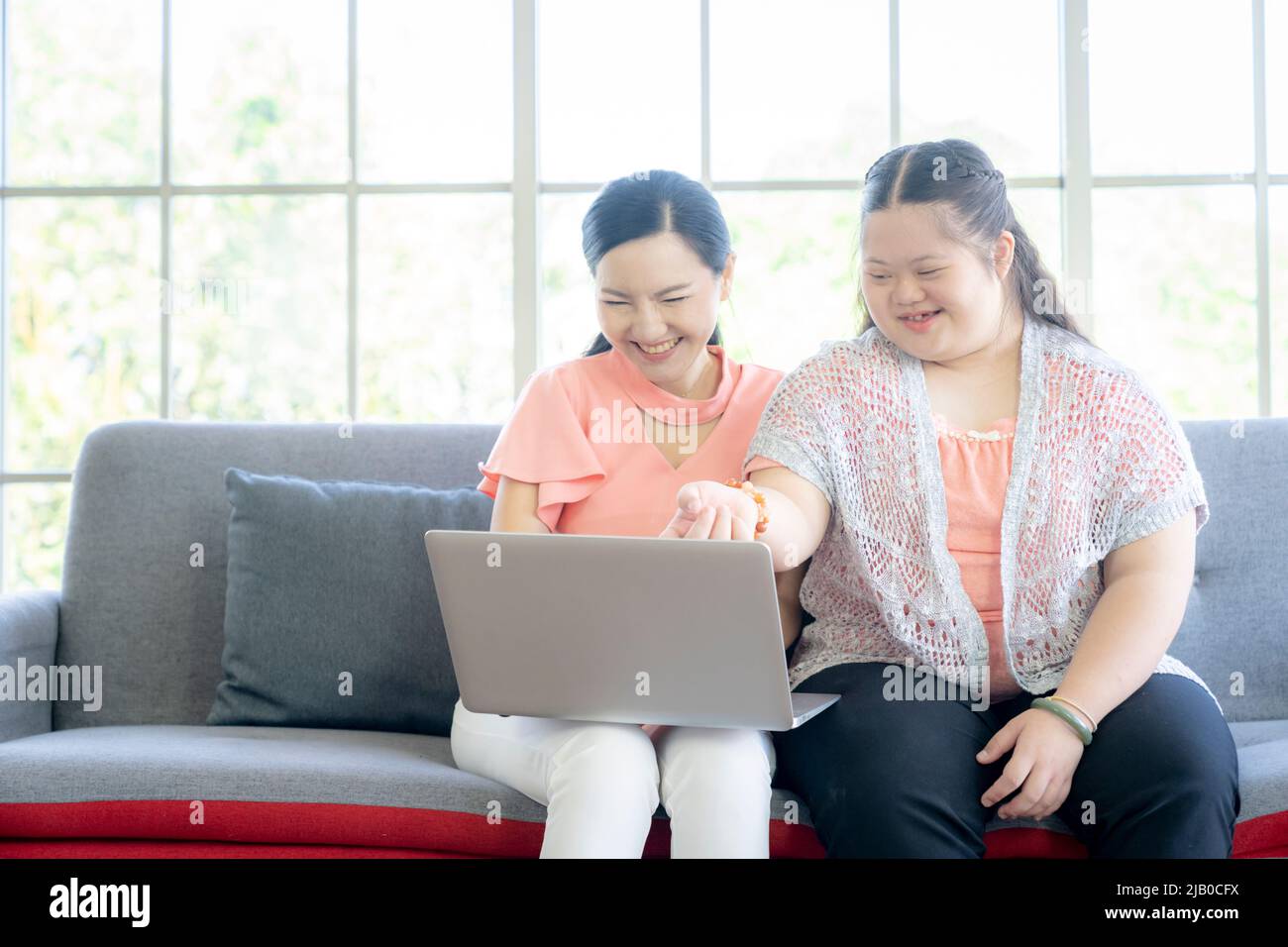 Asian person with Down syndrome using computer with her mom and having ...