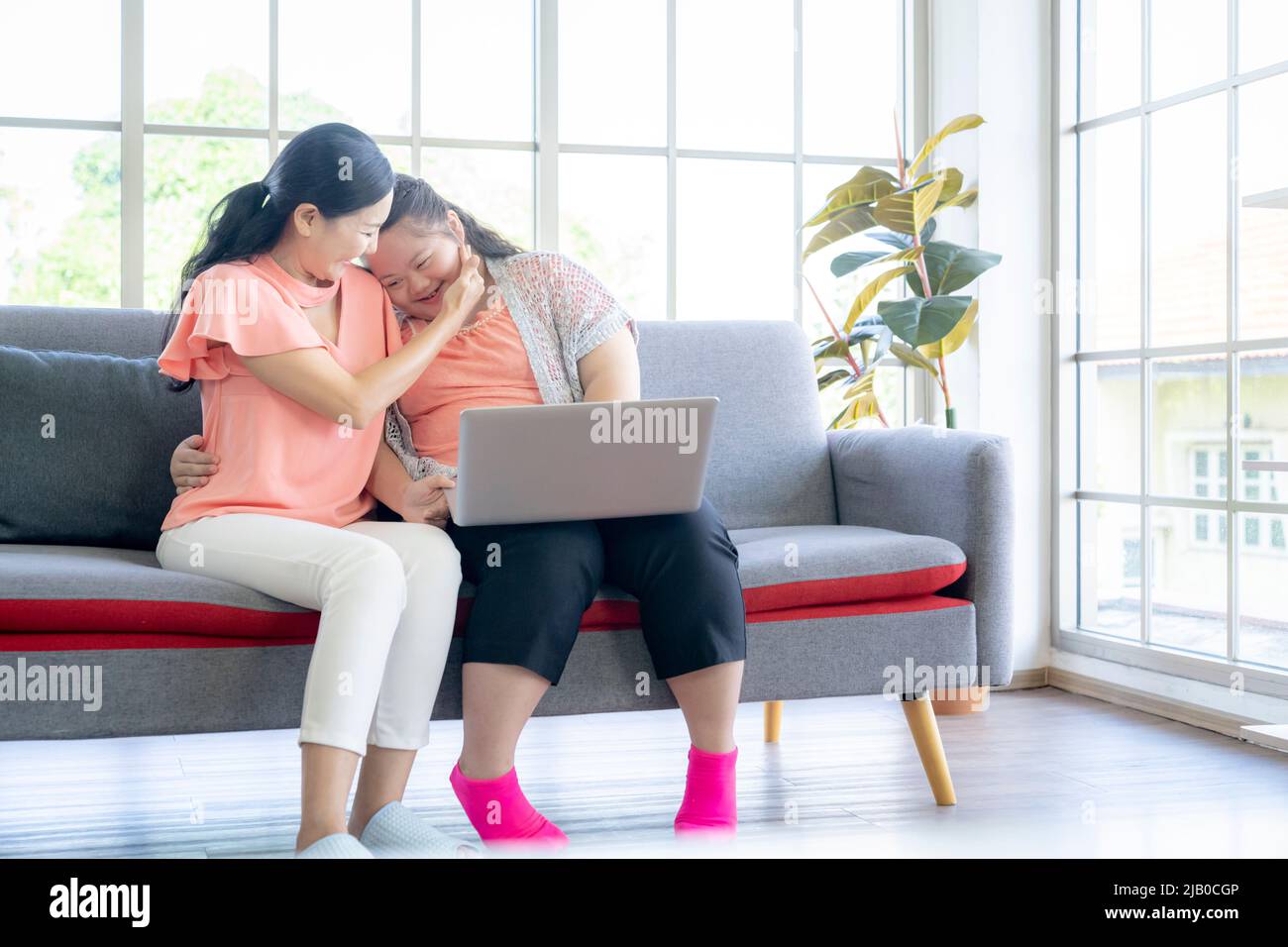 Asian person with Down syndrome using computer with her mom and having ...