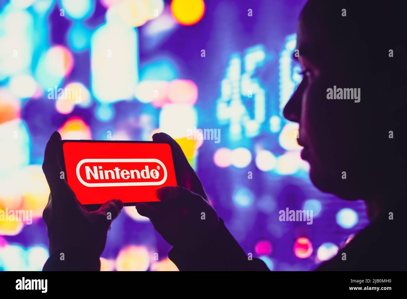 In this photo illustration, a silhouetted woman holds a smartphone with ...