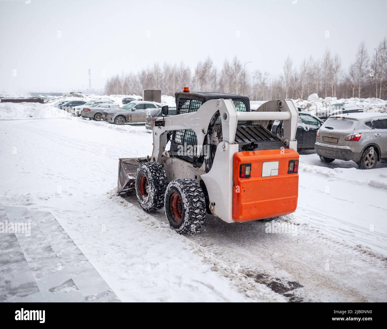Small snow removal vehicle removing snow on city square. Yellow or ...