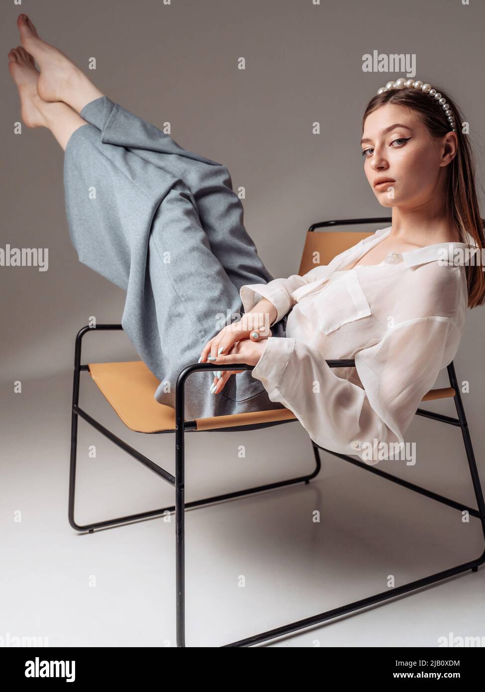 Feet up. Casual young woman sits barefoot on a comfortable armchair ...