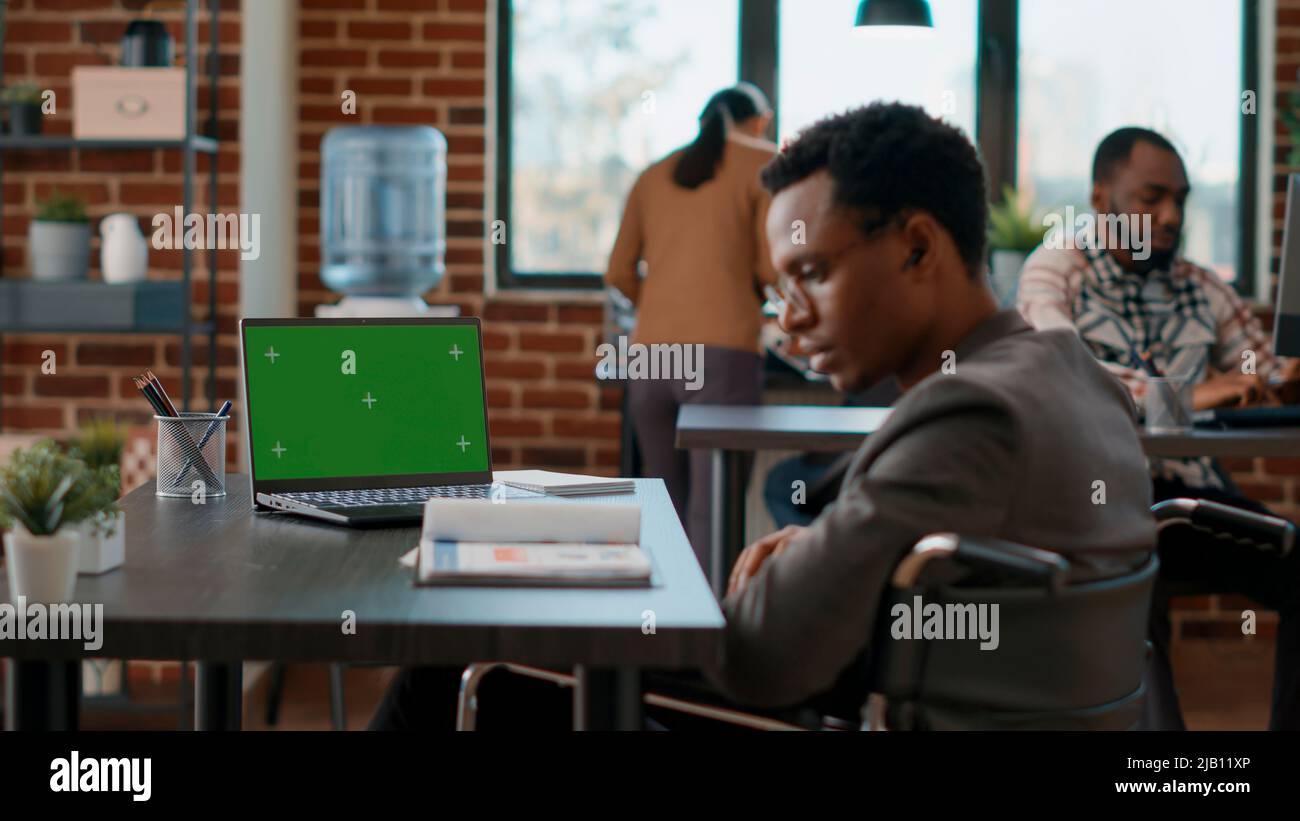Company employee analyzing greenscreen on laptop, working in disability ...