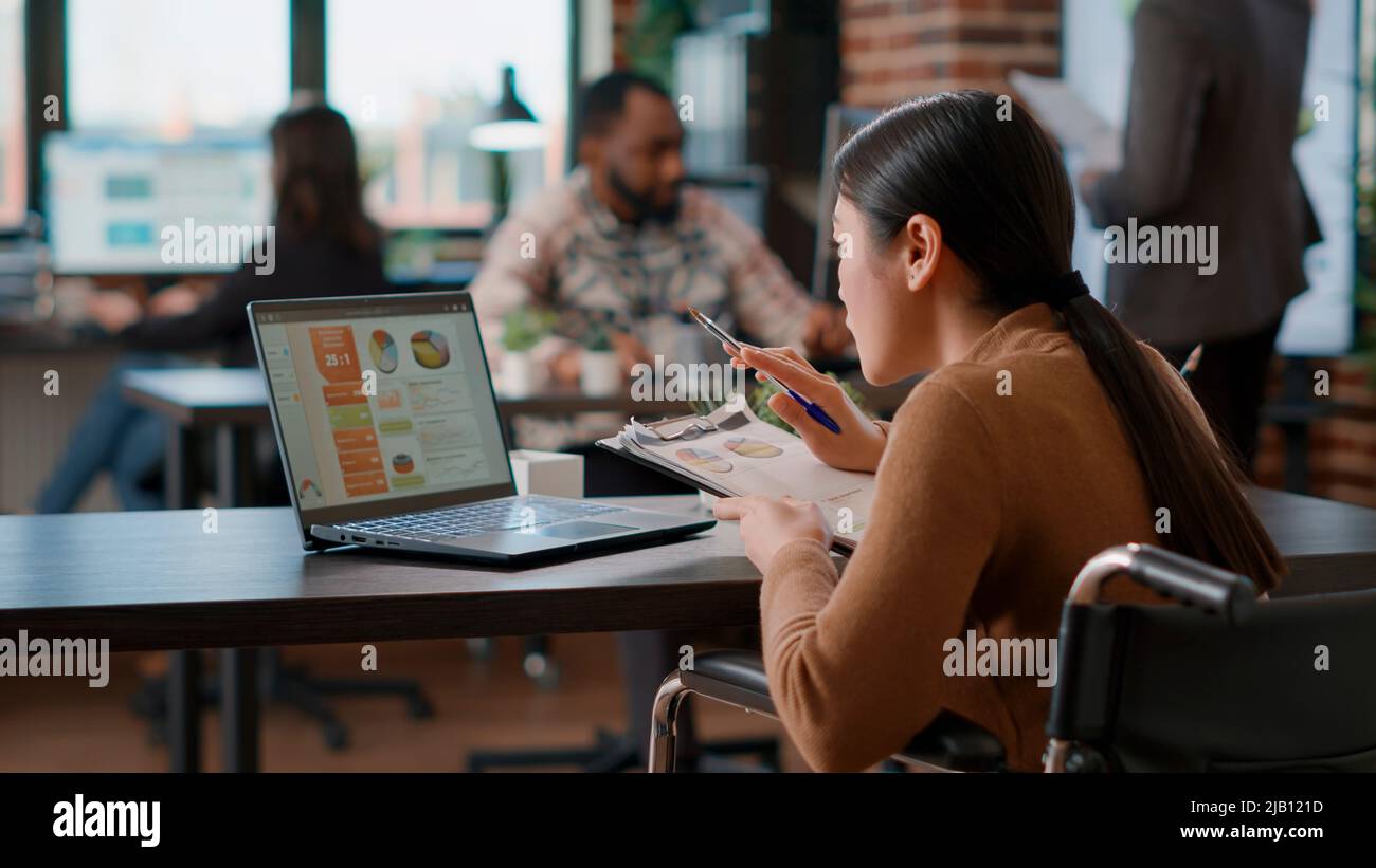 Office worker with disability analyzing business charts on laptop ...