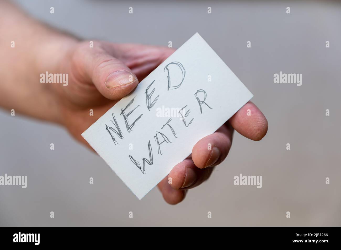 Need water. Words written in jagged letters. A man's hand holds a white ...
