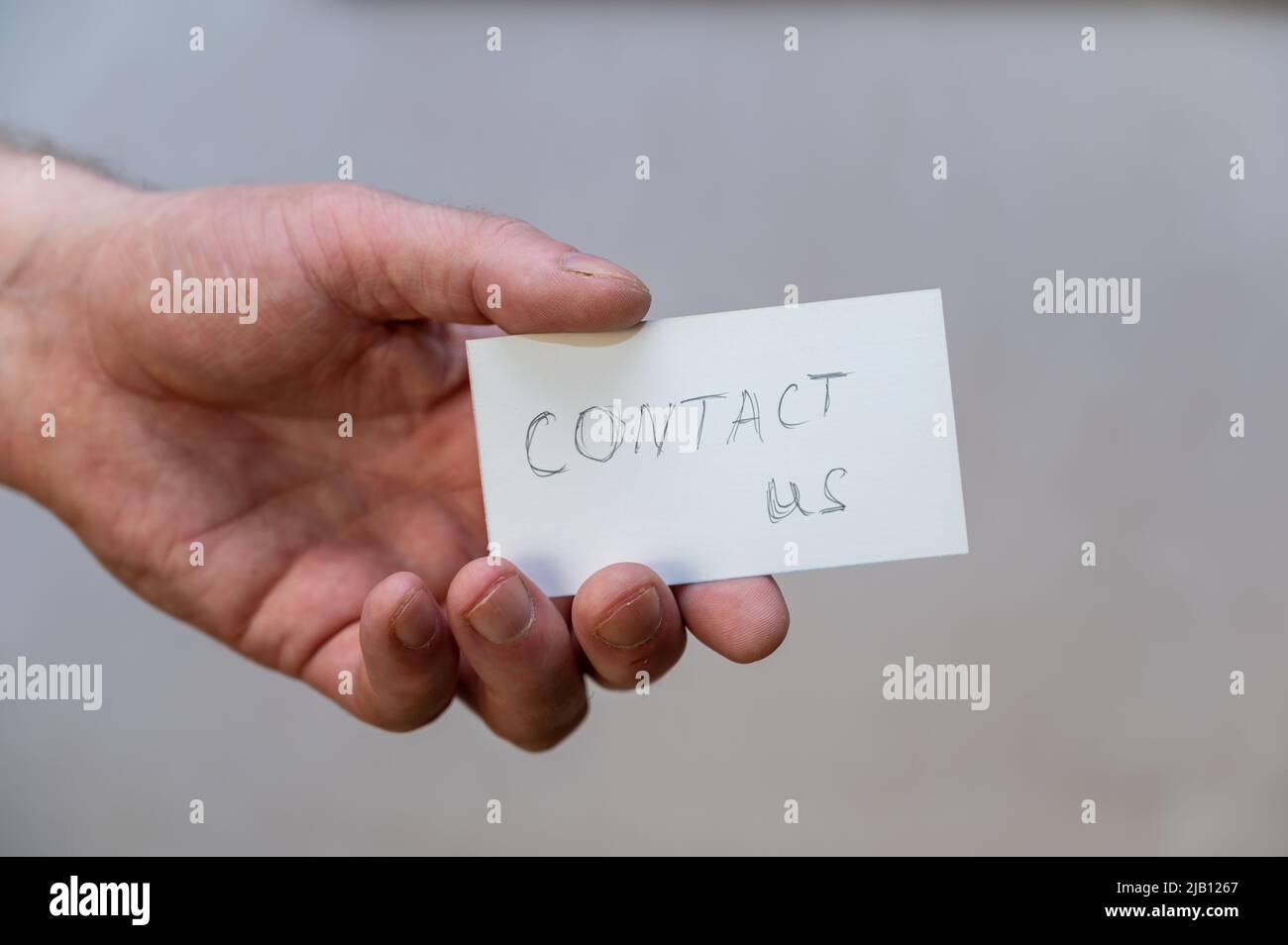 Contact us. Words written in jagged letters. A man's hand holds a white ...