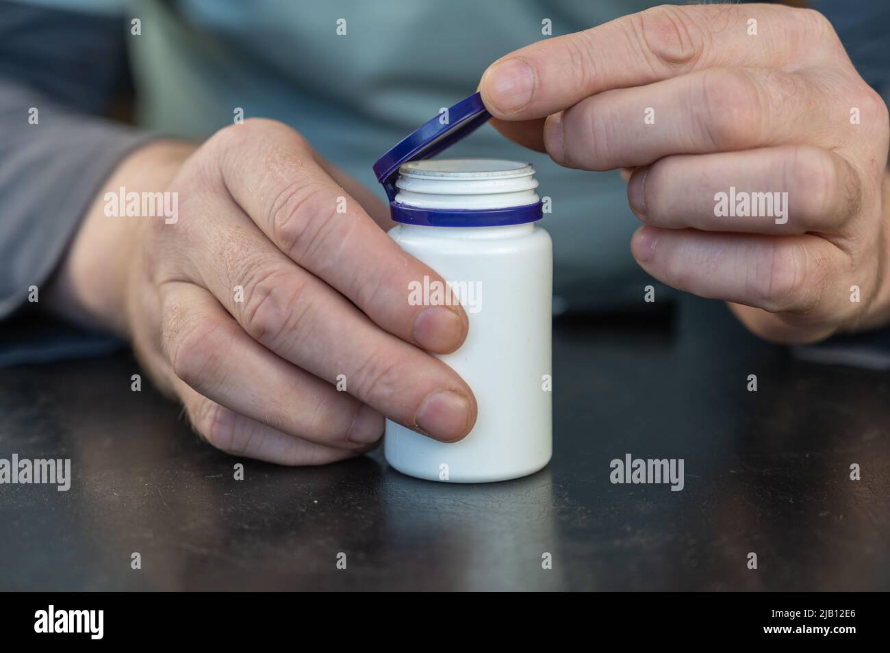 An adult man holds a white vial in his hands Stock Photo - Alamy