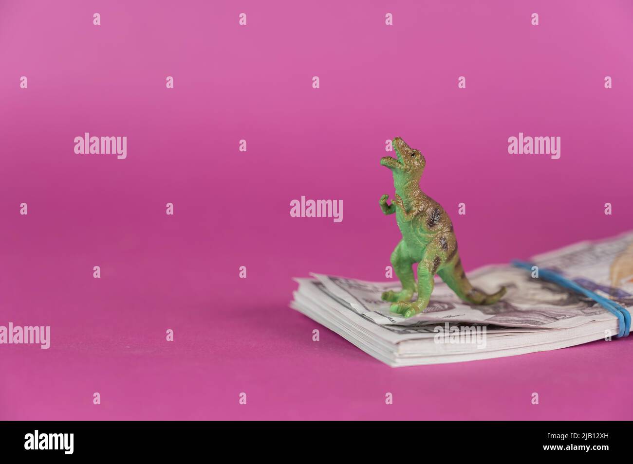 A dinosaur and a wad of cash against a purple background. A stack of ...