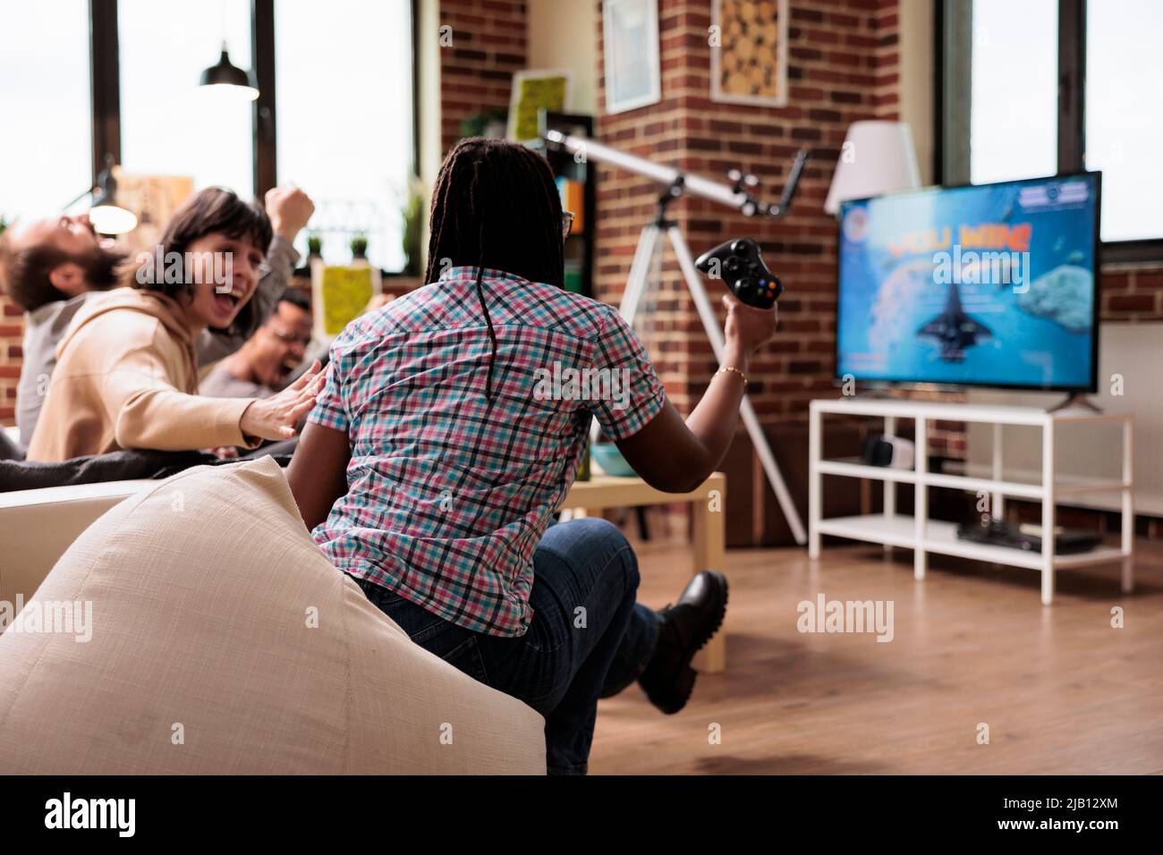 Playful women on sofa playing space simulator videogame on console ...