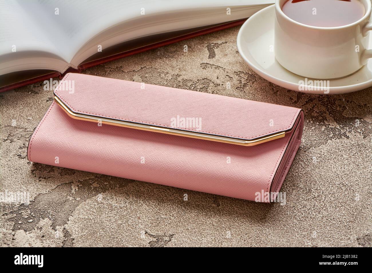 A pink woman's purse lies on a concrete background with a cup of coffee ...