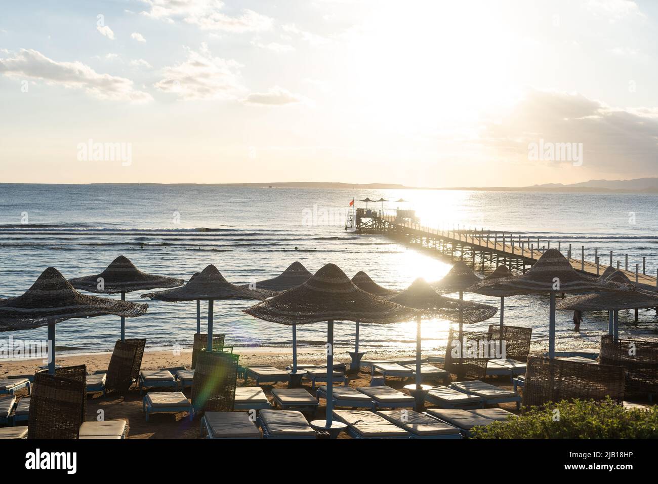 Mediterranean coast with sunbeds and straw sun umbrellas on the sandy ...