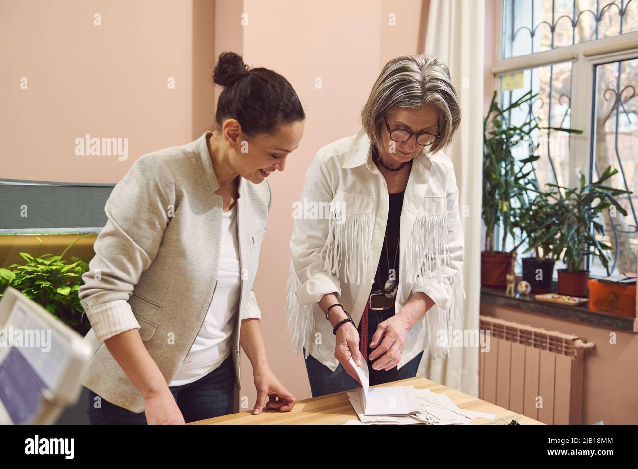 Mature Caucasian woman senior fashion designer and her colleague tailor ...