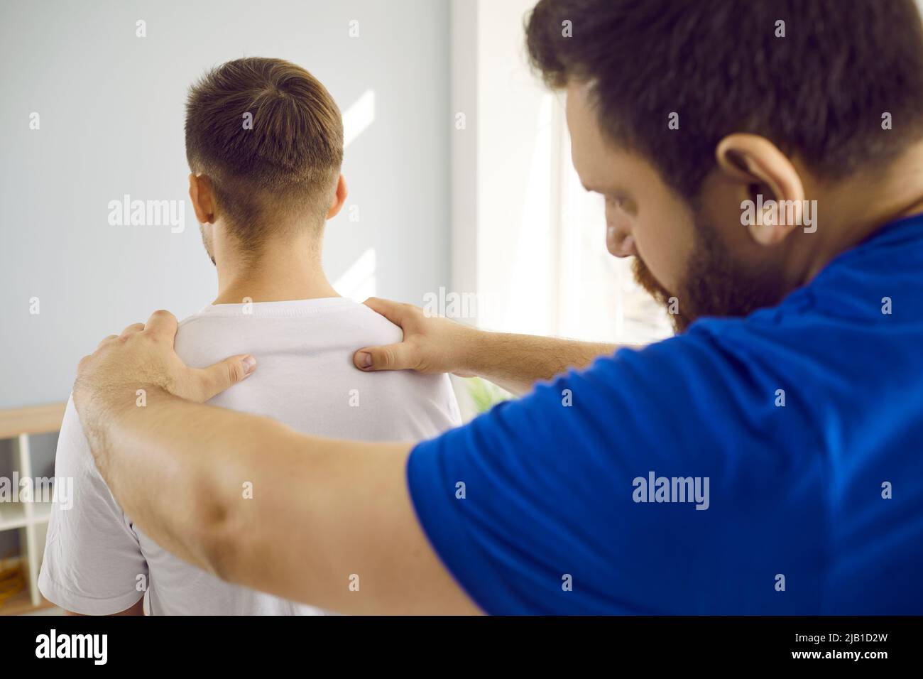 Skilled male therapist examining young man's back and appoints ...